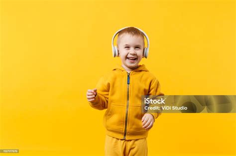 작은 아이가 소년 34 년 된 헤드폰에 노란색 옷을 입고 오렌지 벽 배경 어린이 스튜디오 초상화에 고립 사람들이 진심으 감정 어린 시절 라이프 스타일 개념 복사 공간을 모의