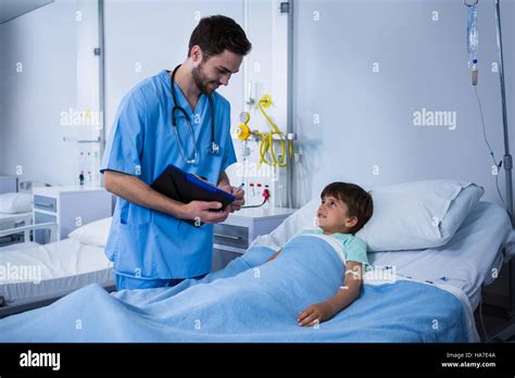 Male Nurse Interacting With Patient During Visit In Ward Stock Photo