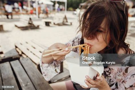 대나무 젓가락으로 판지 상자에서 야채와 해산물을 먹고 웍 국수를 먹는 세련 된 힙 스 터 소녀 아시아 거리 음식 축제입니다 종이