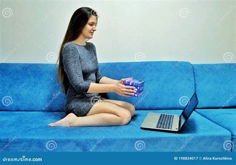 Young Girl Sitting In Dress On Sofa With T In Her Hands In Front Of