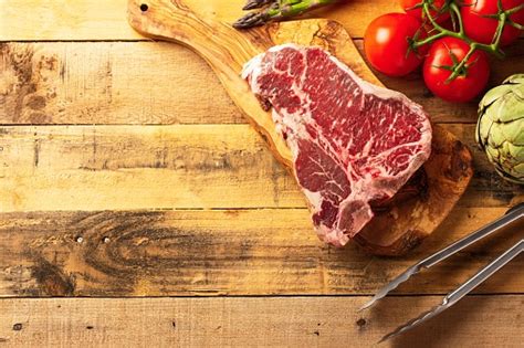 나무 배경에 신선한 야채와 집게와 대리석 쇠고기 스테이크의 신선한 원시 조각 도마에 레스토랑 메뉴 홈 메뉴 맛있는 음식 미식 요리 배경 고기에 대한 스톡 사진 및 기타