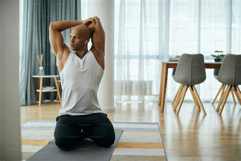 집에서 운동하는 동안 스트레칭 운동을 하는 젊은 아프리카계 미국인 스포츠맨 사진 Unsplash의 성인 이미지