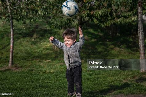 풀밭에서 축구공을 공중에 던지는 행복한 아이의 전신 모습 공원에서 스포츠를 즐기는 아이가 공중에서 점프하면서 날아가는 축구공을