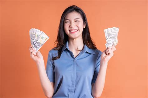 오렌지 배경에 포즈를 취하는 젊은 아시아 비즈니스 우먼 프리미엄 사진