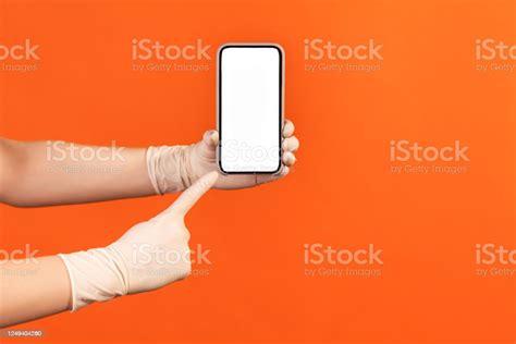 흰색 수술 장갑에 인간의 손의 프로필 측면 보기 는 스마트 폰을 잡고 보여주는 빈 디스플레이를 가리킵니다 가리키기에 대한 스톡