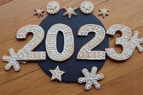 나무 테이블에 검은 슬레이트 돌판에 숫자 2023의 형태로 설탕 유약 장식이 있는 진저브레드 쿠키 0명에 대한 스톡 사진 및