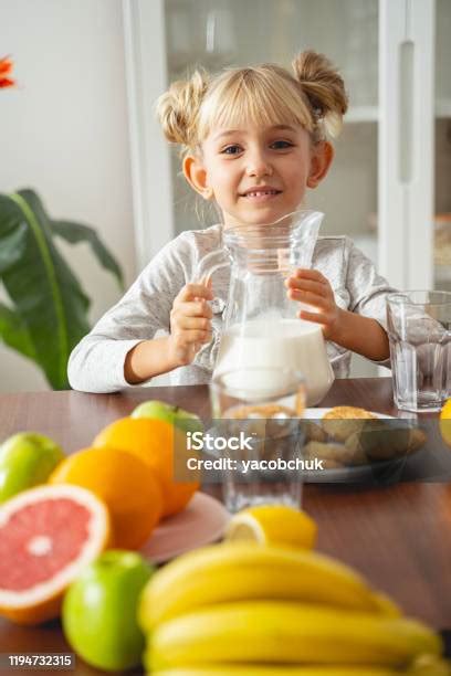 Gadis Kecil Yang Gembira Duduk Di Meja Dapur Di Rumah Foto Stok Unduh