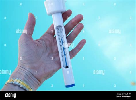 Checking The Temperature Of The Swimming Pool Water With A Thermometer