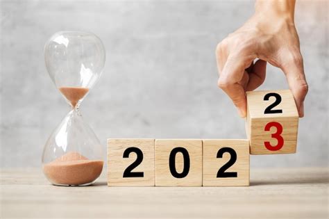 Premium Photo Hand Flipping Block 2022 To 2023 Text With Hourglass On