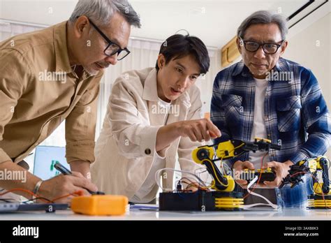 Asian Robot Arm Engineers Brainstorming In Workshop To Develop Control Technology With Teamwork