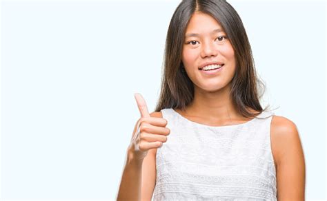 행복 한 엄지손가락 손으로 제스처를 하 고 격리 된 배경 위에 젊은 아시아 여자 승인 성공을 보여주는 카메라를 보고 하는 식