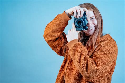 파란 바탕에 카메라를 들고 있는 한 젊은 여성이 우리를 마주보고 서 있는 사진을 찍고 있다 20 24세에 대한 스톡 사진 및