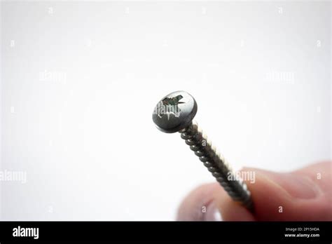 Small Metal Threaded Screw Held By Caucasian Male Hand Between Fingers