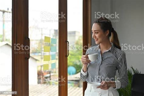 커피 한 잔을 들고 창문 밖으로 사려 깊은 표정을 짓는 인도 아시아 여성 비즈니스 및 재무 개념 커피 시간에 대한 스톡 사진 및