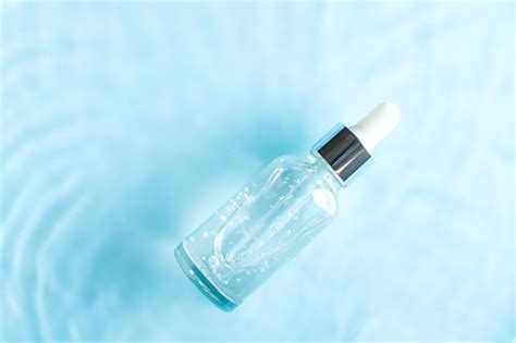 화장품 스파 의료 스킨 케어 세럼이 든 병 미셀라 토너 및 에센스가 블루 워터 텍스처 배경에 튀어 나옵니다 플랫 레이 복사 공간