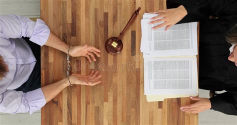 Convict Is Handcuffed And Judge Pronounces Sentence On Wooden Table Top