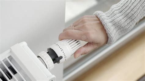 A Woman Adjusts The Radiator Thermostat To The Maximum Temperature In