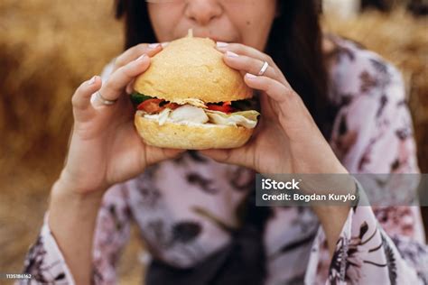 길거리 음식 축제에서 맛 있는 비 건 버거를 먹는 선글라스의 세련 된 소식통 소녀 여름 거리에서 야채와 함께 행복 한 보헤미안 여자 시음과 물고 햄버거 길거리 음식 축제