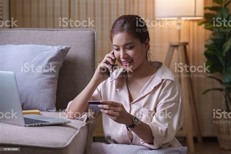 집에서 소파에 앉아 신용카드와 스마트폰으로 온라인 쇼핑을 하는 예쁜 아시아 여성 Brand Name Smart Phone에 대한