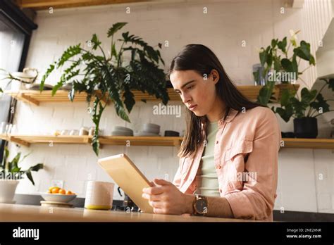 Non Binary Trans Woman Using Digital Tablet In The Kitchen At Home Concept Of Gender Fluidity