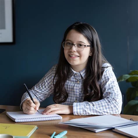 Premium Photo A Girl Sits At A Table With A Pen In Her Hand And A Pen