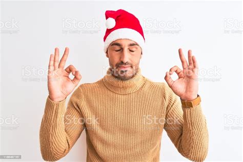 고립 된 배경 위에 크리스마스와 터틀넥 스웨터를 입은 젊은 잘생긴 남자는 손가락으로 명상 제스처를하고 눈을 감고 미소 요가 개념입니다 남자에 대한 스톡 사진 및 기타 이미지