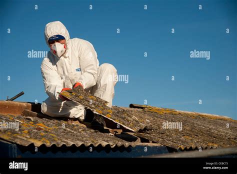 A Workman Wearing Protective Clothing And Facemask Removing Asbestos