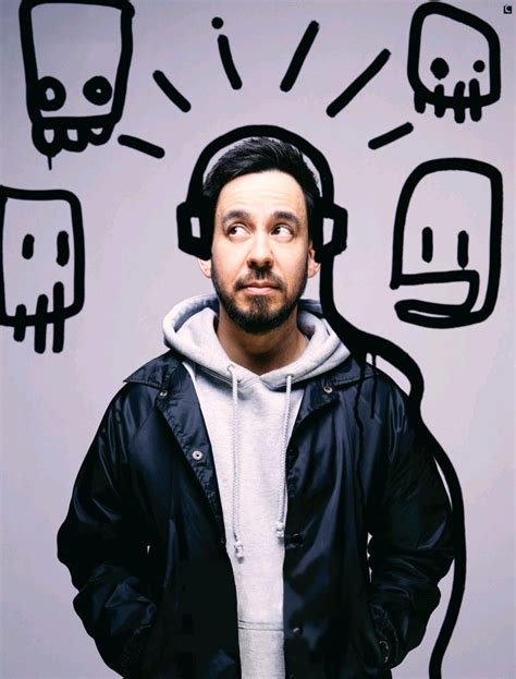 A Man With Headphones On Standing In Front Of A Drawing Of Skulls And Heads