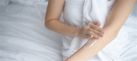 Asia Woman Sitting On Bed And Applying Cream On Her Body Stock Image