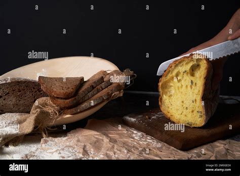 Mens Hands Cut A Loaf Of Bread On A Cutting Board On A Dark Black Background Copy Space The