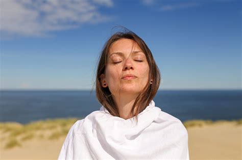 눈을 감고 흰 천으로 감싸 아름 다운 어두운 머리 젊은 흰색 유럽 여자 닫습니다 리투아니아의 니다 에 있는 파 니 디스 듄에 게로 탄 침에서 촬영 푸른 하늘과 맑은 날