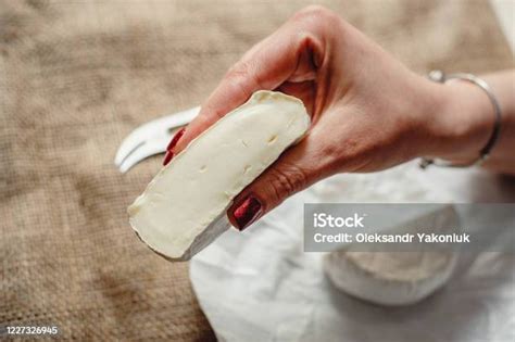 컷 카망베르 치즈 공예 섬유 테이블 보의 배경에 여자의 손에 흰색 곰팡이와 프랑스 소프트 치즈 클로즈업 치즈 를 슬라이스칼