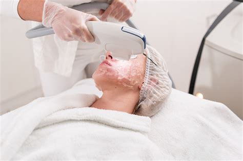 의사는 환자에게 특별한 젤을 적용합니다 전문 장비와 안티 여드름 광선 요법 사진 회춘 절차 동안 아름다운 여자입니다 미용 클리닉에서 얼굴 피부 치료 건강관리와 의술에 대한