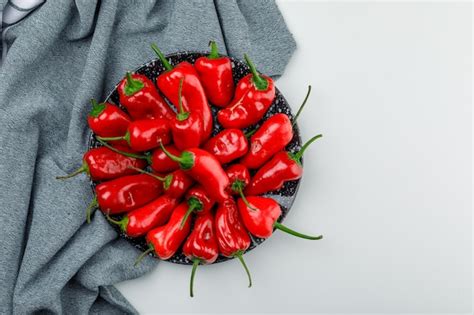 Красные перцы в плите на стене белизны и ткани, взгляд сверху ...
