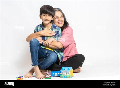 Portrait Of Happy Indian Grandmother And Grandson Hug Sit On Floor