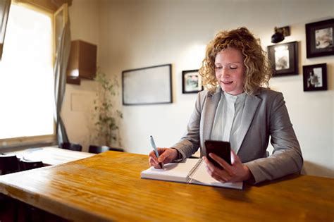 그녀의 개인 주최자에 쓰는 동안 휴대 전화를 사용하여 백인 사업가 30 34세에 대한 스톡 사진 및 기타 이미지 30 34세 35 39세 결심 Istock