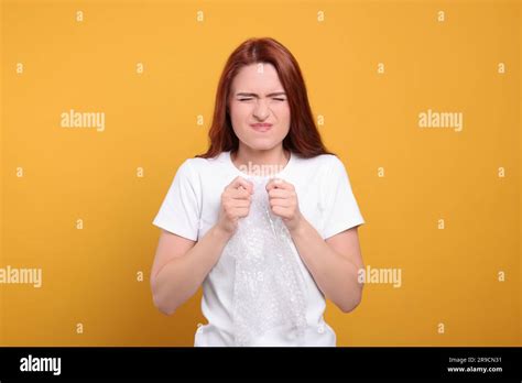 Angry Woman Popping Bubble Wrap On Yellow Background Stress Relief