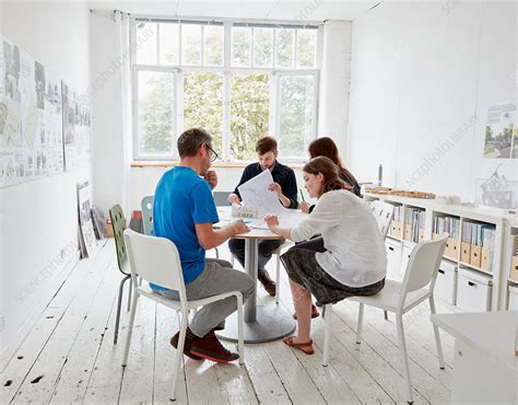 Two Men And Two Women At A Table With Plans And Papers Stock Image F018 4009 Science Photo