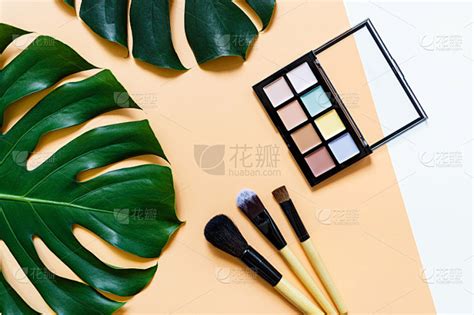 化妆的背景。眼影调色板，粉，笔刷，黄色背景上的口红。平铺，俯视图与复制空间。时尚、美容、化妆、化妆品