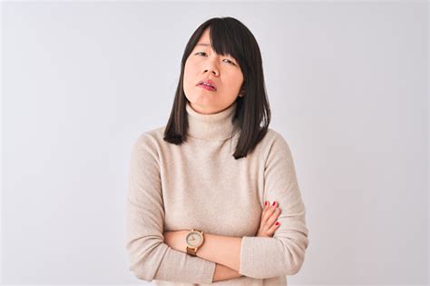 고립 된 흰색 배경 회의론자 및 긴장 교차 된 팔로 얼굴에 표정을 거부 위에 터틀넥 스웨터를 입고 젊은 아름다운 중국 여성