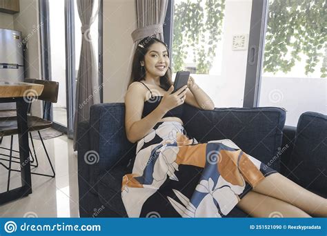 Young Asian Woman Spend Her Free Time At Home Sitting On A Cozy Sofa In