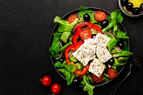 페타 치즈 올리브 체리 토마토 파프리카 오이 붉은 양파 건강한 식물성 지중해 식단 낮은 칼로리를 곁들인 그리스 샐러드 블랙 스톤 배경 상단 보기 복사 공간 건강한 식생활에