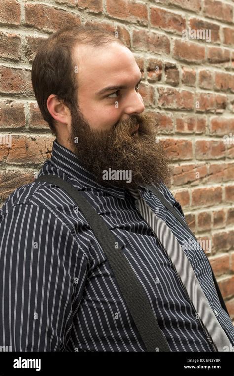 Well Dressed Bearded Man Stares A Sinister Stare Against Textured Brick
