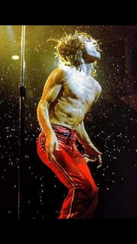 A Man With No Shirt On Standing In Front Of A Microphone And Wearing