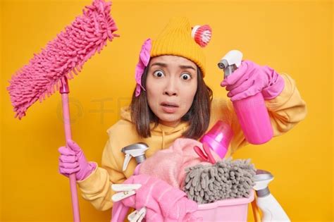 困惑高清图片 令人印象深刻的亚洲女性的室内照片看起来对非常脏的表面感到困惑使用分配器在周末进行洗衣在假期前进行春季大扫除使用拖把洗地板