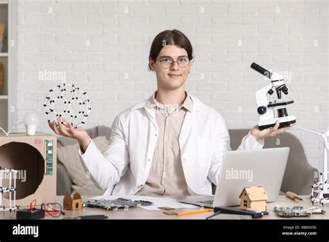 Male Inventor With Molecular Model And Microscope At Table In Office Male Inventor With Molecular Model And Microscope At Table In Office