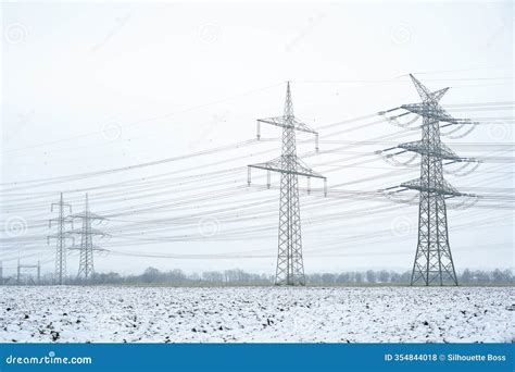 Overhead Transmission Winter Electrical Energy Tower And High Voltage Lines On The Field And
