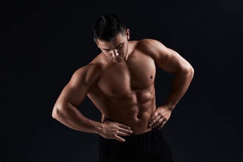 Fisiculturista muscular em preto Forte homem atlético mostra corpo