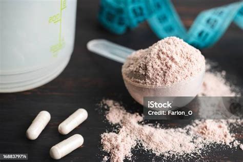 초콜릿 유청 단백질 분리 스쿱 아미노산 크레아틴 및 측정 테이프의 흰색 캡슐 어두운 나무 판에 보디 빌딩 식품 보조제 가루로