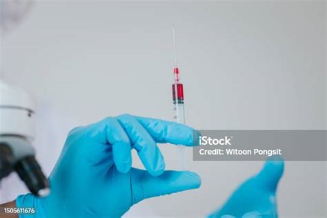 의사가 실험실에 있는 분석기가 있는 선반에서 혈액 샘플 튜브를 꺼냅니다 연구실에서 혈액 검사관을 들고 있는 기술자 Dna에 대한